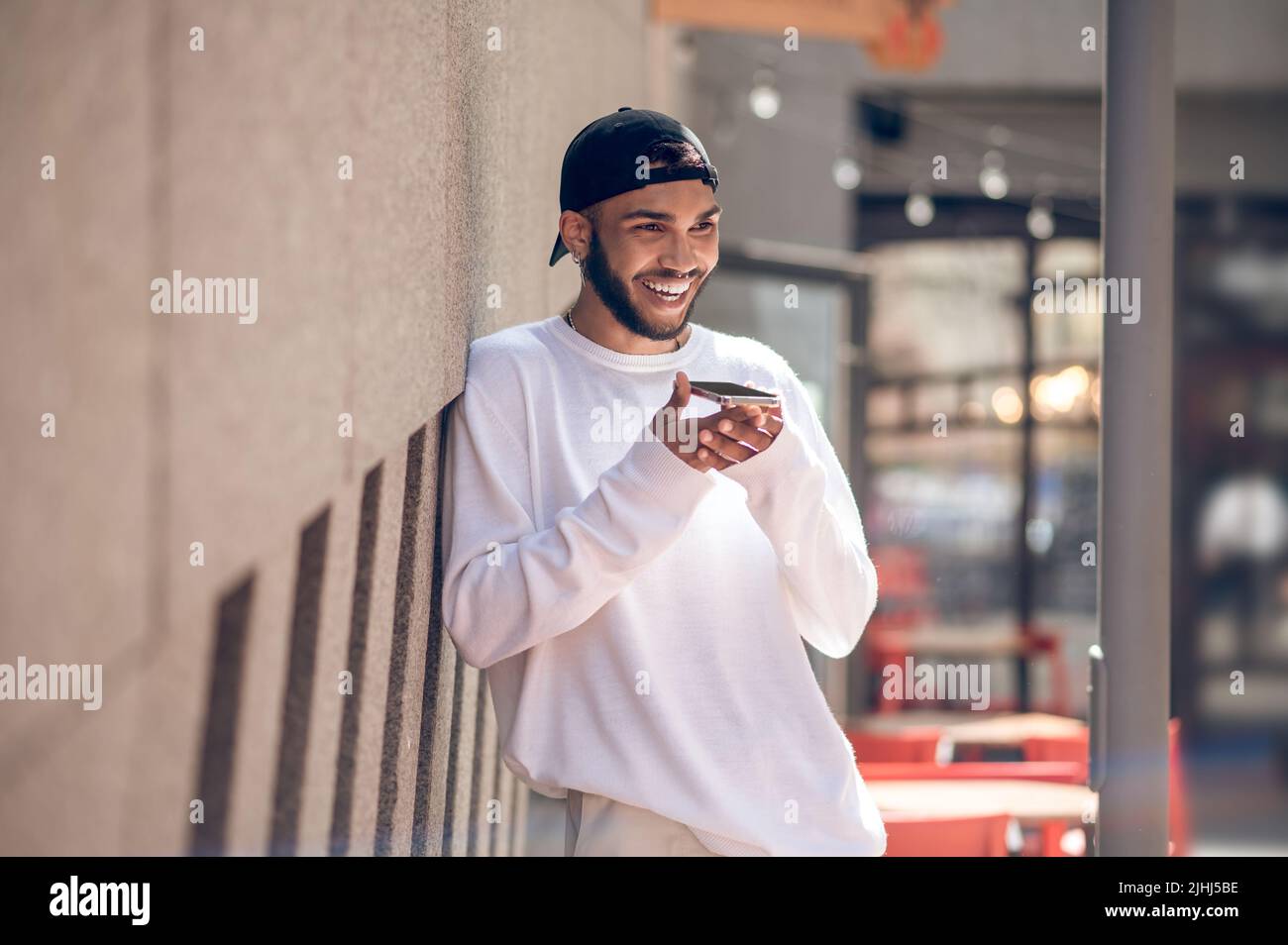 Handsome man in a black cap with a smartphone in the street Stock Photo ...