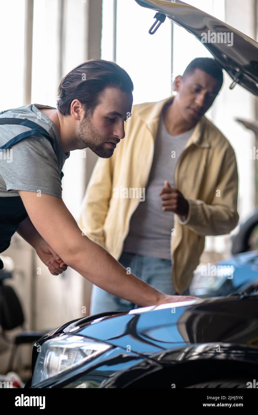Mechanic identifying car problem and excited customer Stock Photo - Alamy