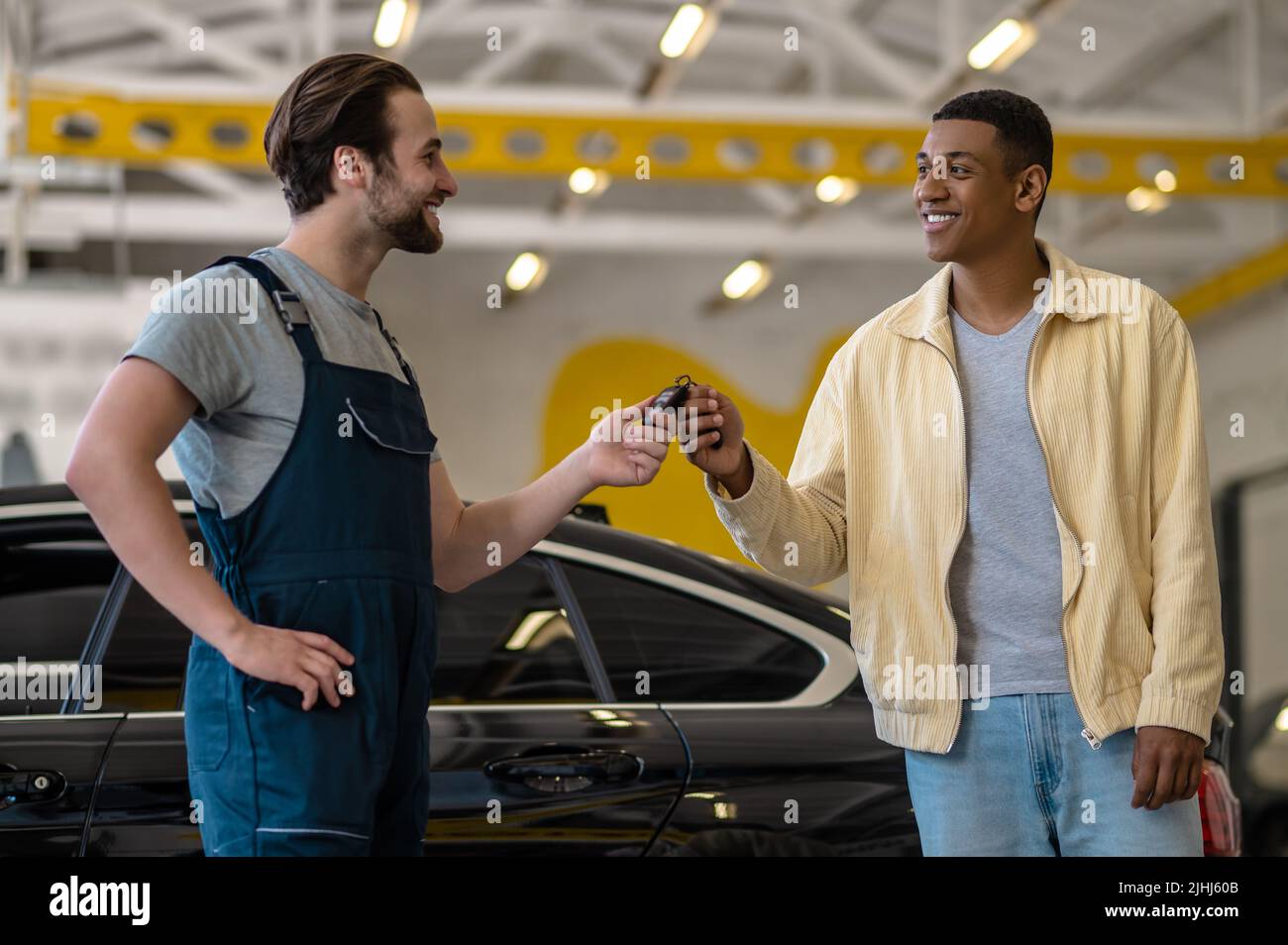 Two men standing sideways to camera touching key Stock Photo - Alamy