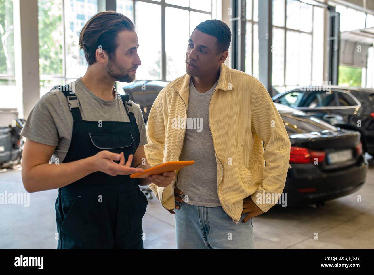 Mechanic with clipboard asking thoughtful customer Stock Photo - Alamy