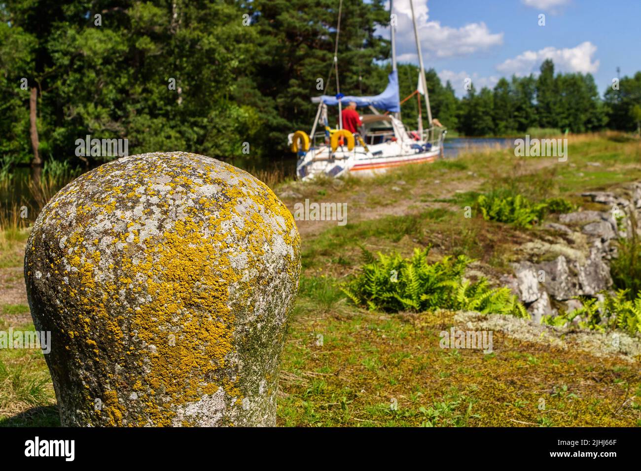 Old stone bollar at a canal with a sailboat Stock Photo - Alamy