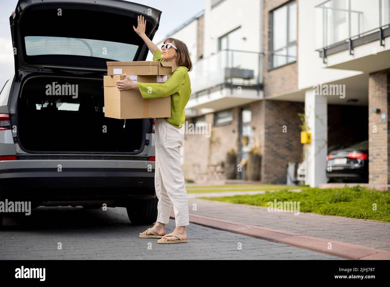 Woman taking parcels from a car trunk Stock Photo - Alamy