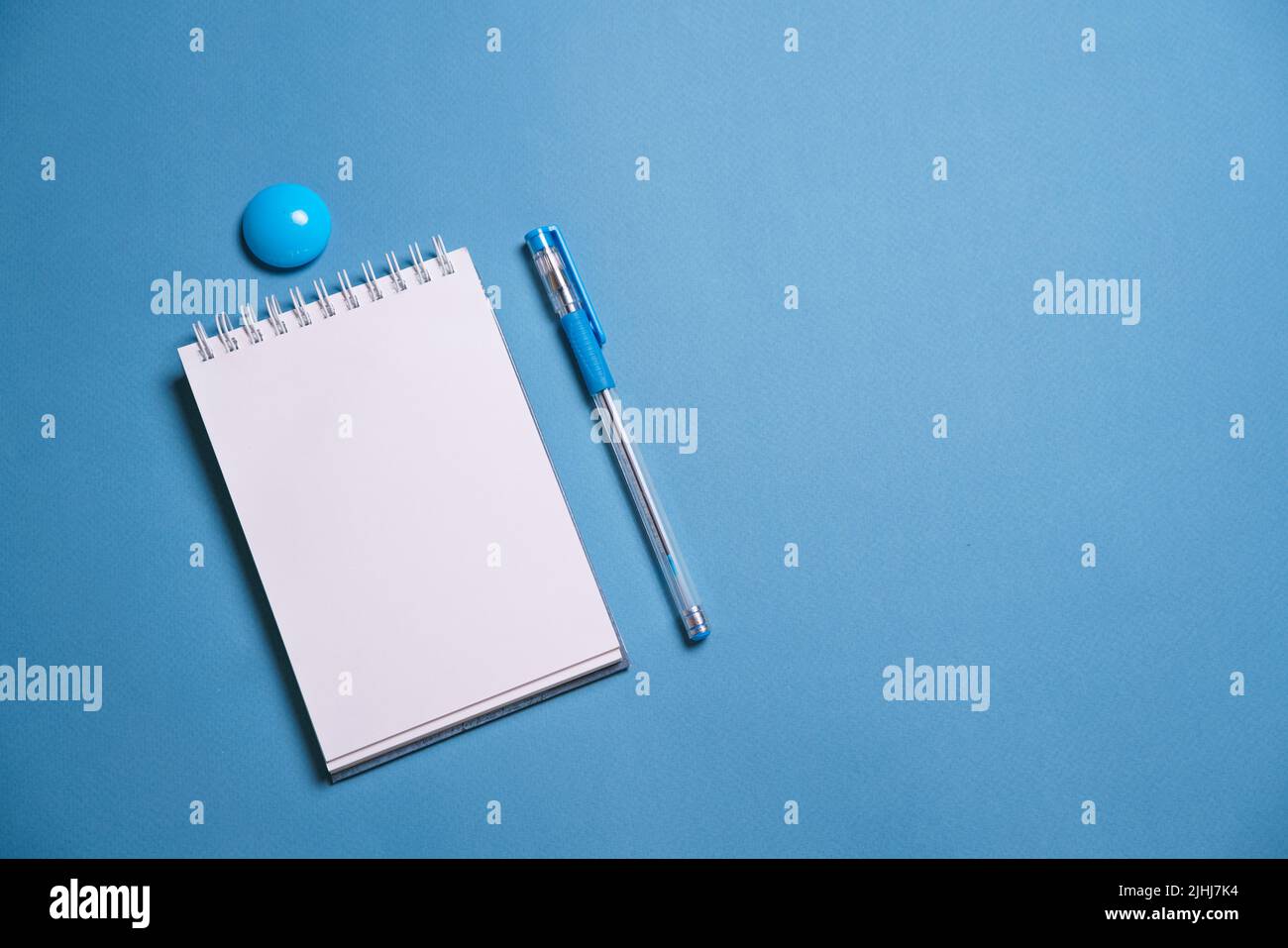 Notebook and pen on a blue background. Top view with copy space ...