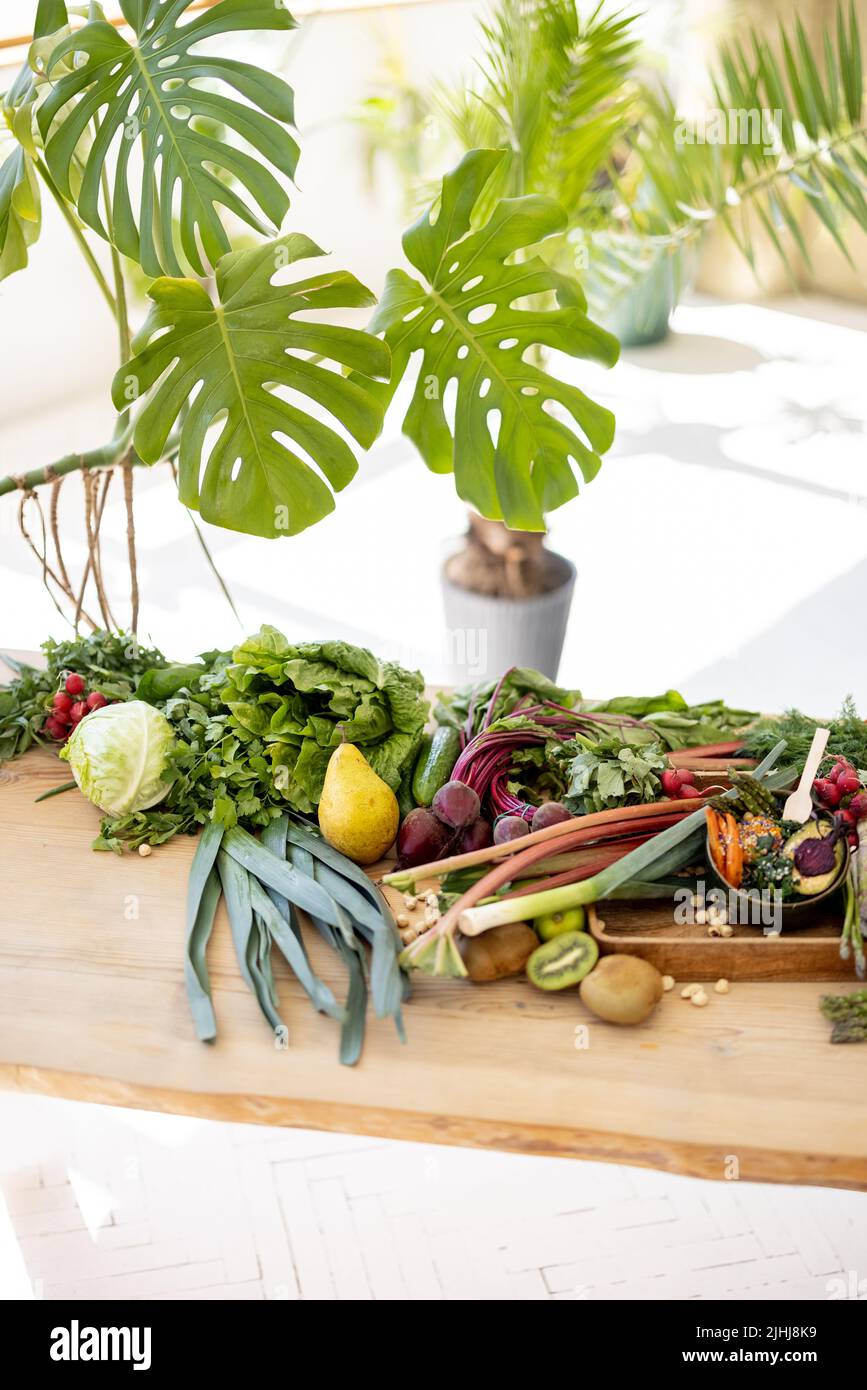 Lots of fresh vegetables, fruits and greens on table indoors Stock ...