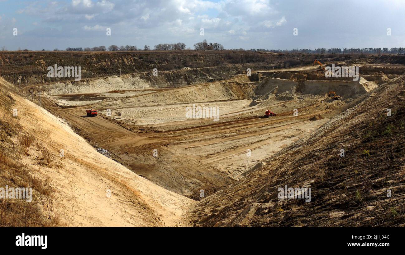 Top view of open air clay pit with mining excavators under blue sky ...