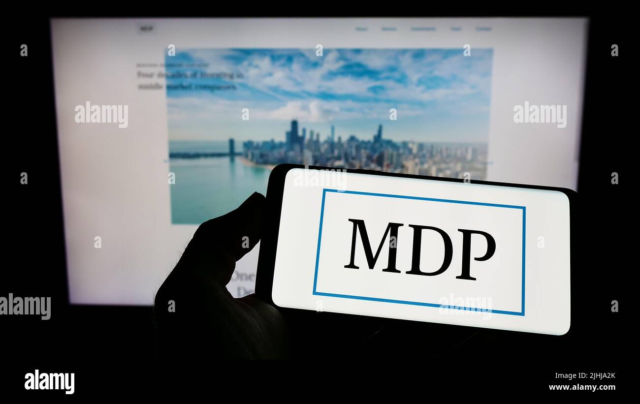 Person holding smartphone with logo of US company Madison Dearborn ...