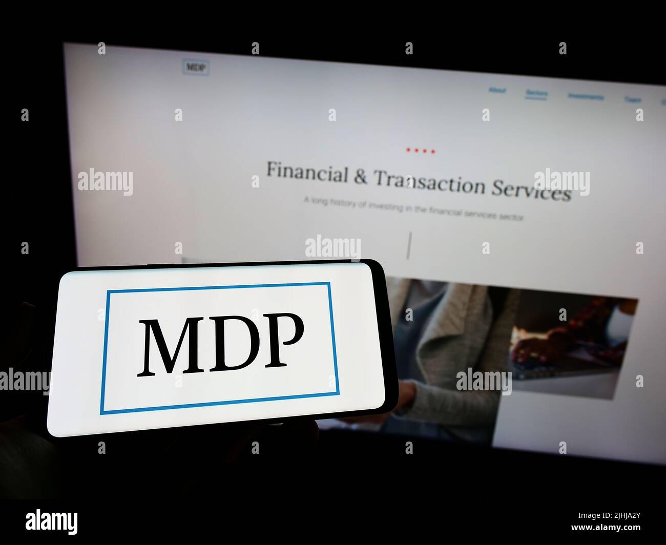 Person holding mobile phone with logo of US company Madison Dearborn Partners LLC (MDP) on ...