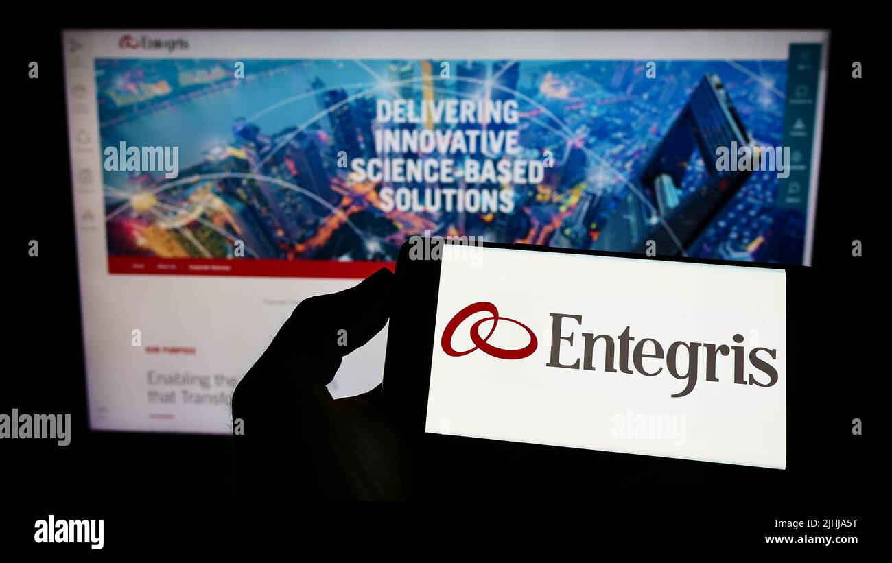 Person holding mobile phone with logo of American microelectronics ...