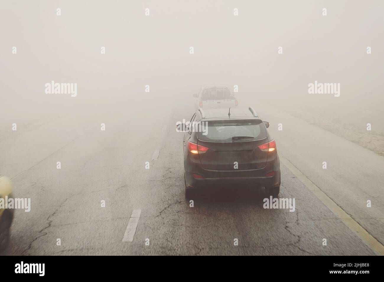 heavy fog on the road. Poor visibility. Silhouette of the car in heavy ...