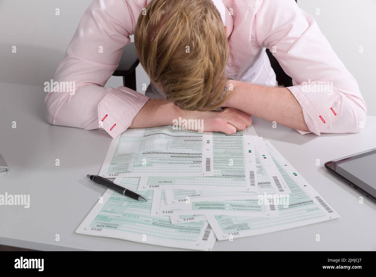 Exhausted young man works hard at his tax declaration on his desk Stock ...