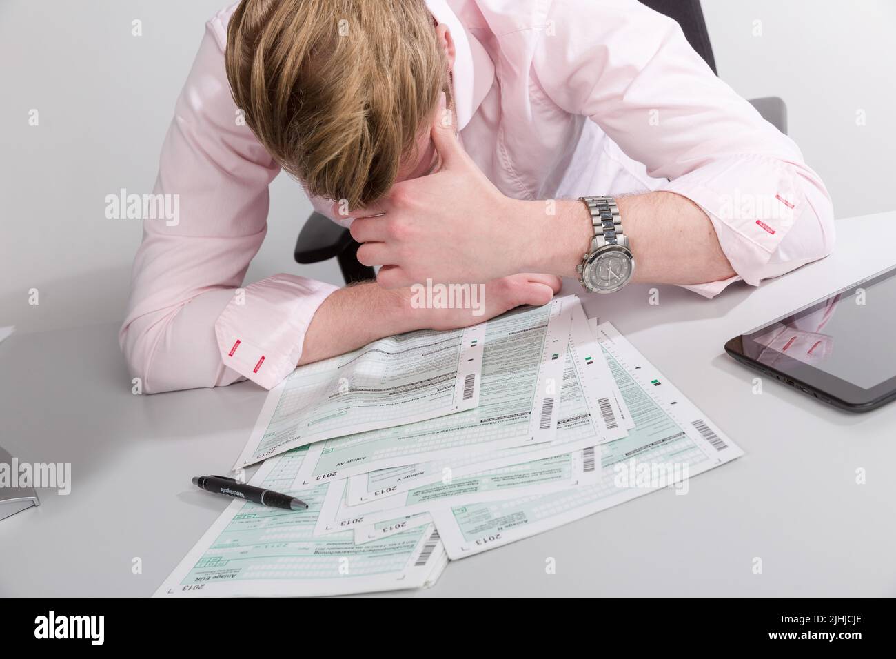 Exhausted young man works hard at his tax declaration on his desk Stock ...