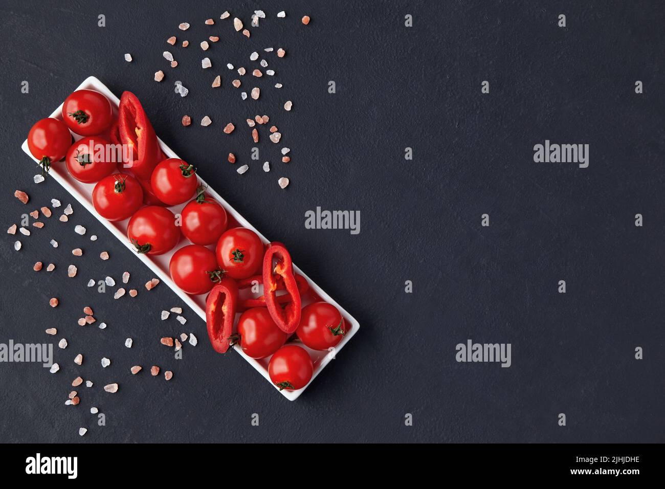 Fresh washed cherry tomatoes and paprika slices on a white oblong dish ...