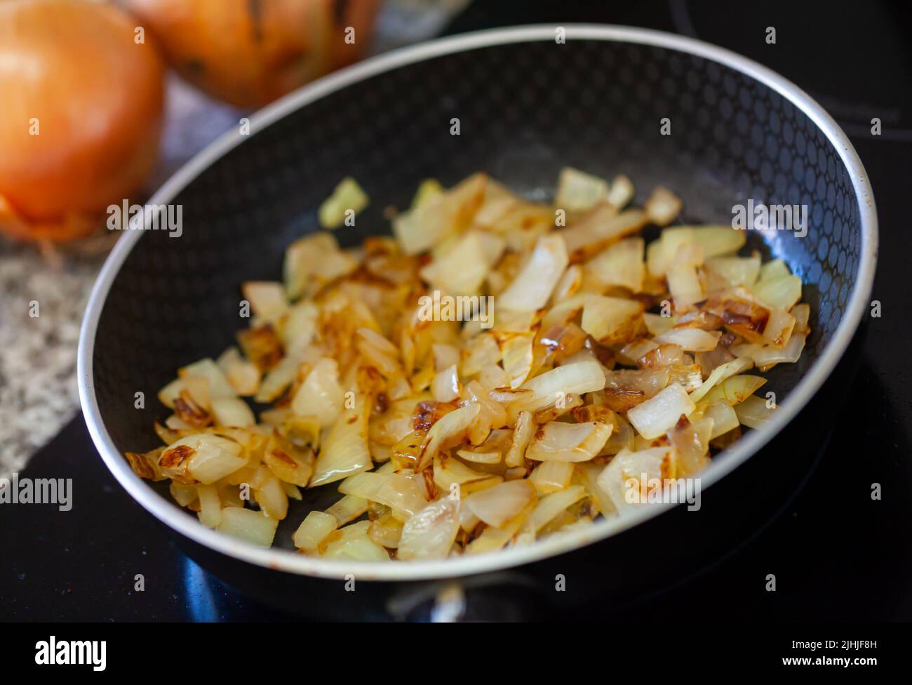 Chopped onions are fried in a black pan Stock Photo - Alamy