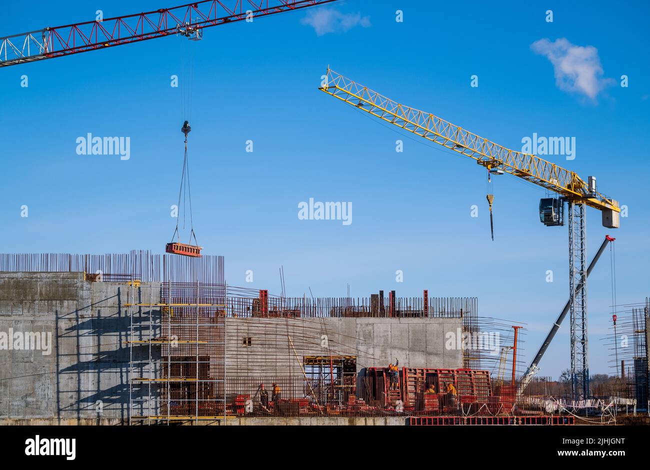 Cranes building structure against blue sky Stock Photo - Alamy