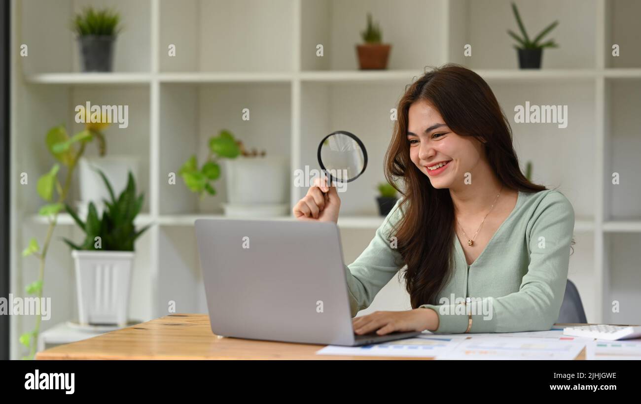 Female Auditor with magnifying glass checking online content on laptop ...