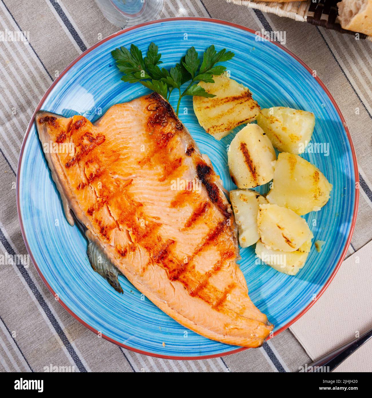 Fried trout fillet with baked potatoes on blue plate Stock Photo - Alamy