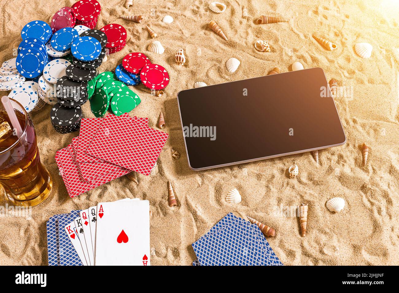 Online poker game on the beach with digital tablet and stacks of chips ...