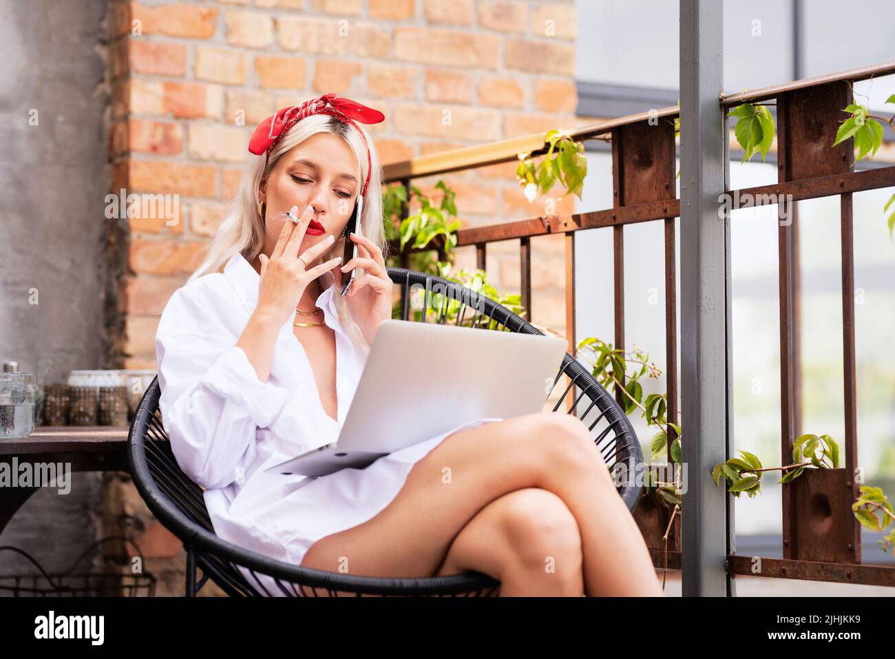 Attractive girl smoking cigarette and having phone call while working ...