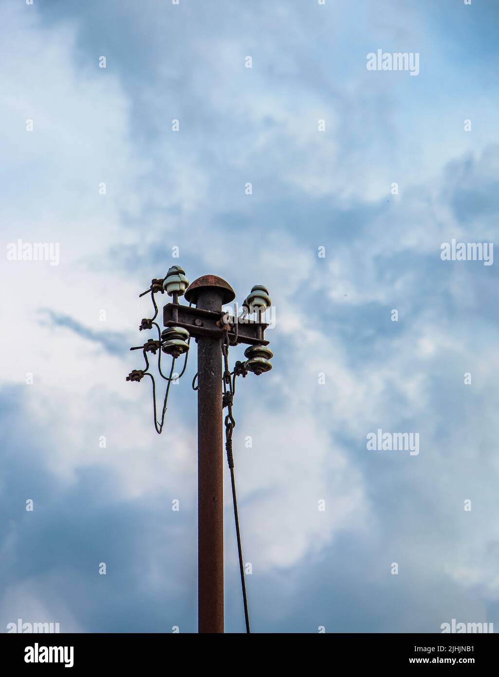 Old street concrete pillar with rusty iron part at top and cut wires ...
