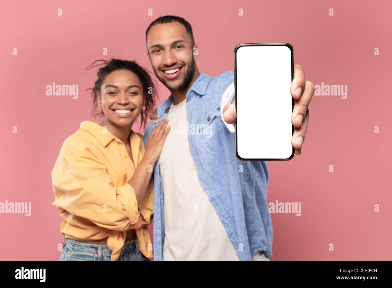 Using cool application. Happy black couple holding smartphone with ...