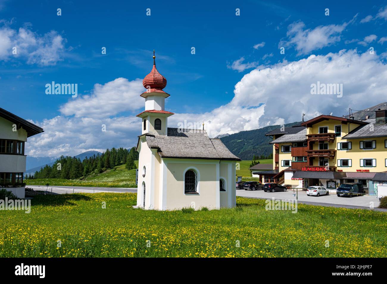 Eine kleine Kapelle und ein Hotel auf einer grünen Wiese am Straßenrand ...