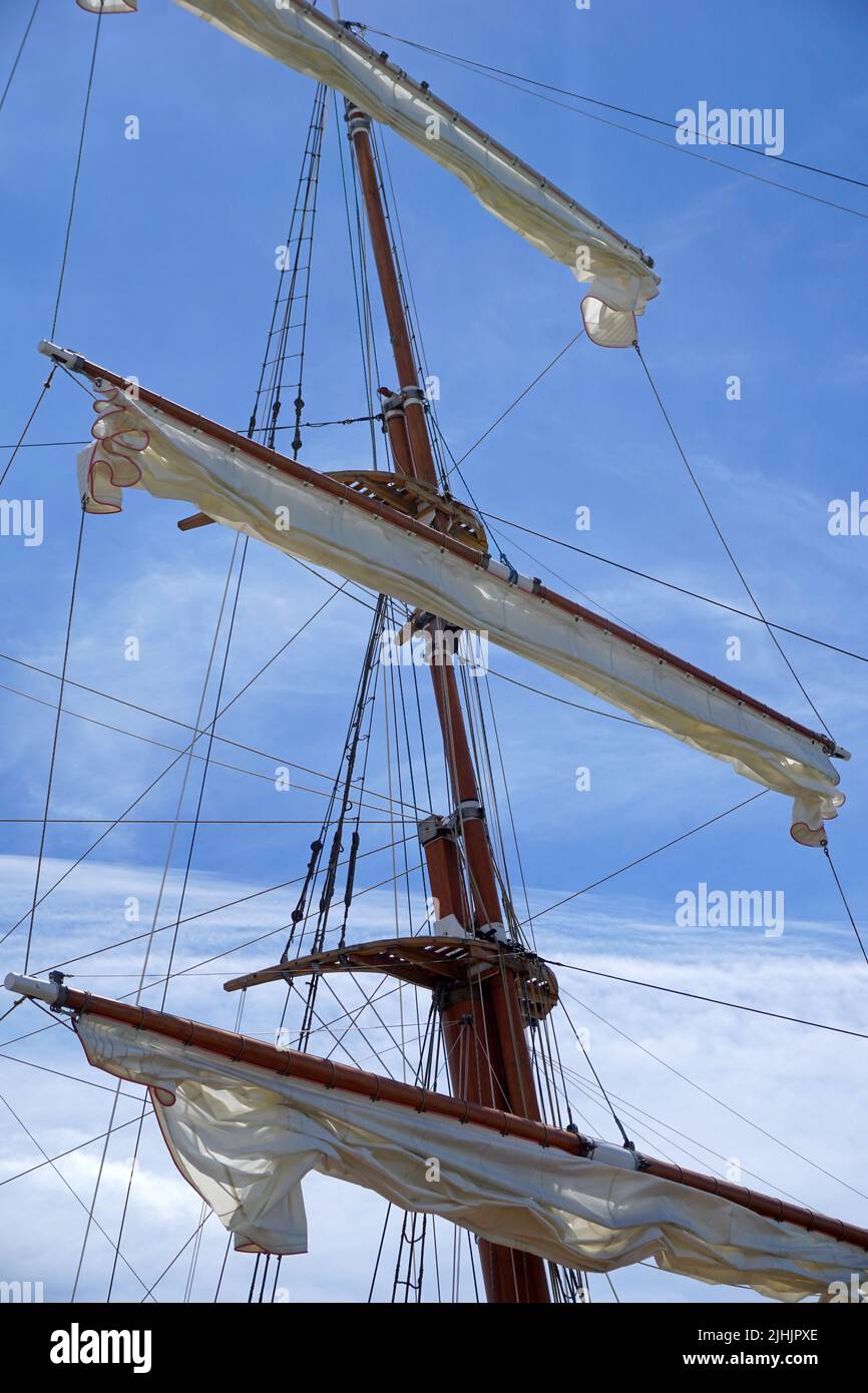 Tall ship mast with rolled sails, sky in background Stock Photo - Alamy