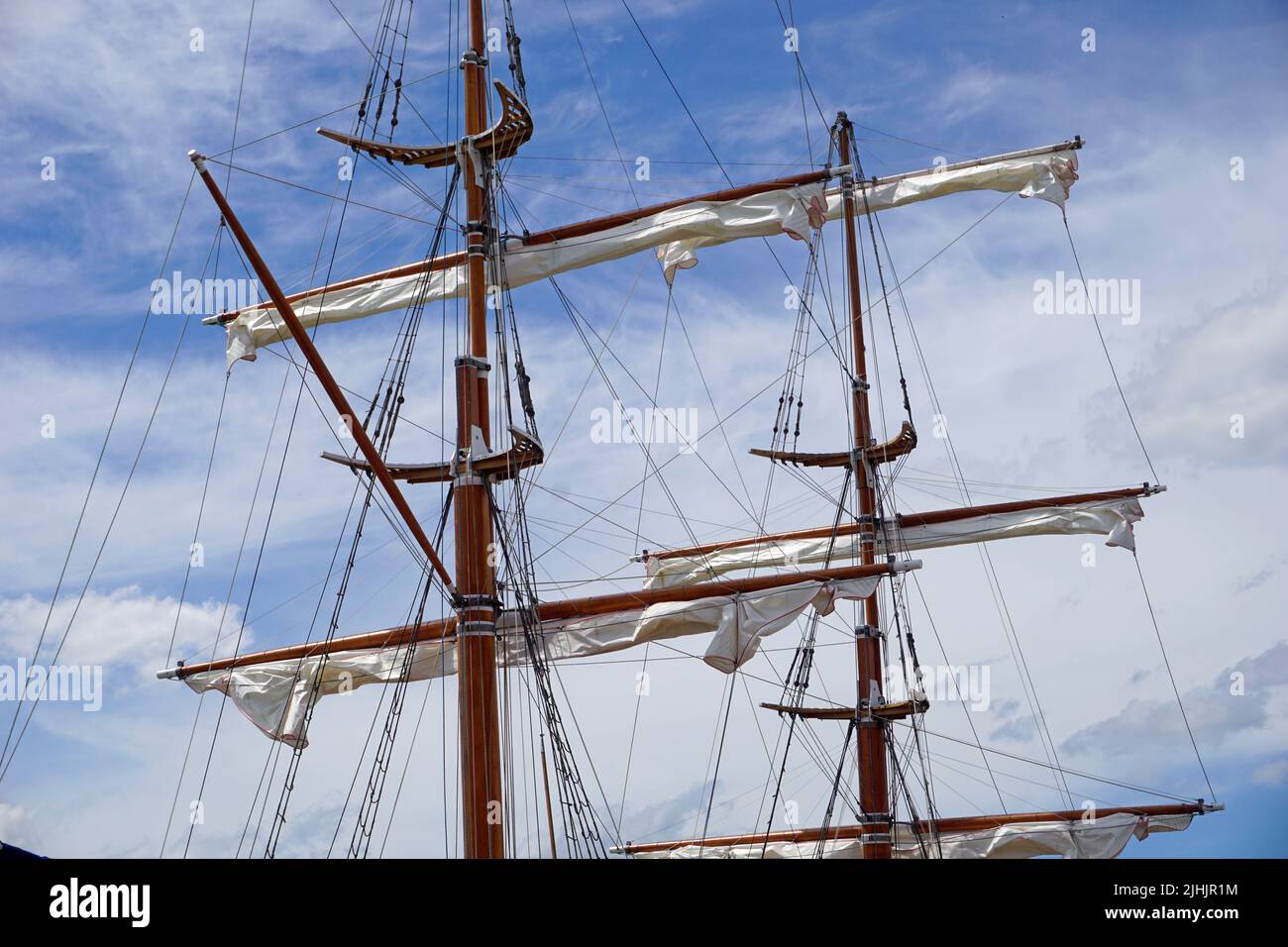 Tall ship mast with rolled sails, sky in background Stock Photo - Alamy