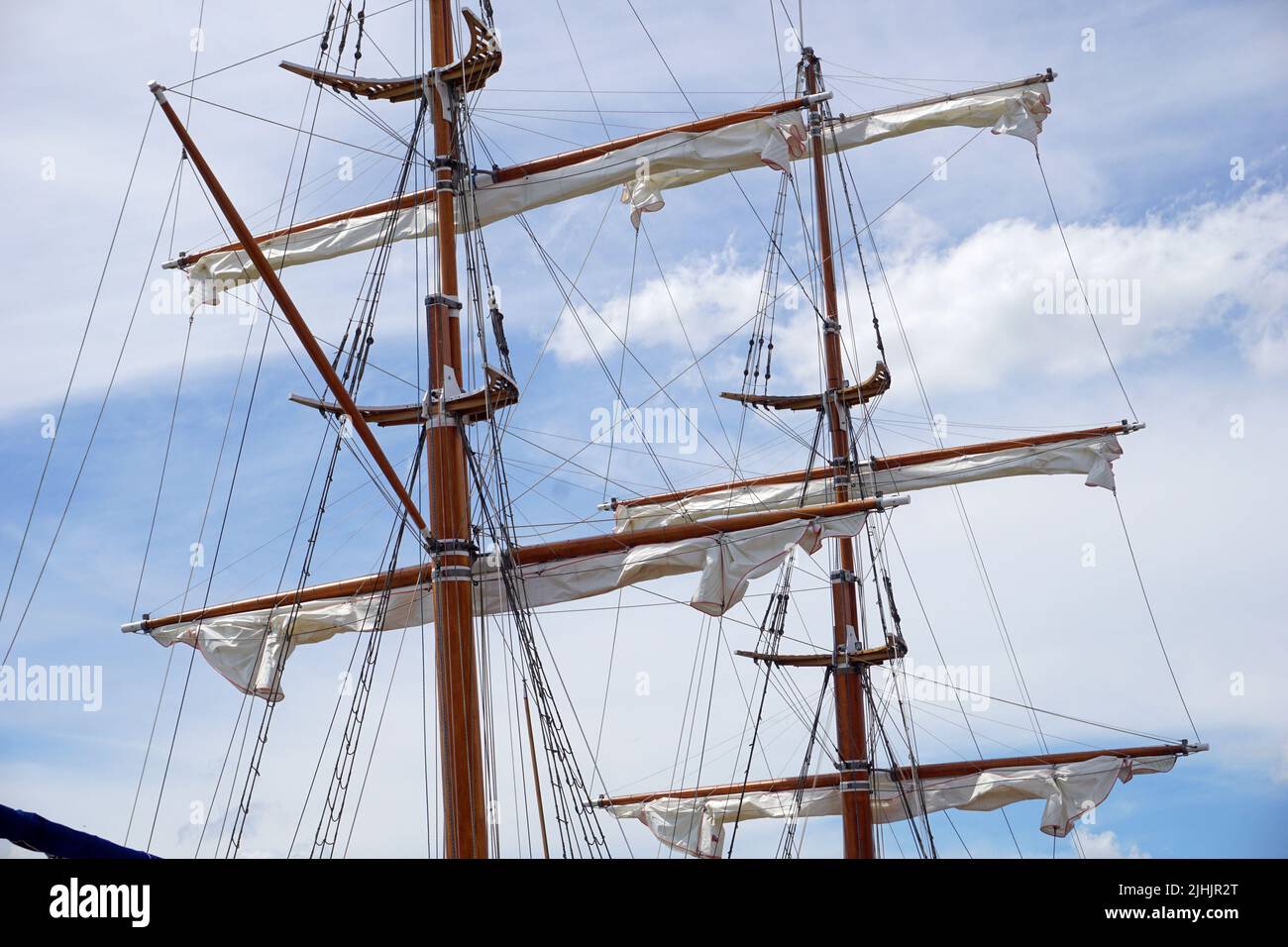 Tall ship mast with rolled sails, sky in background Stock Photo - Alamy
