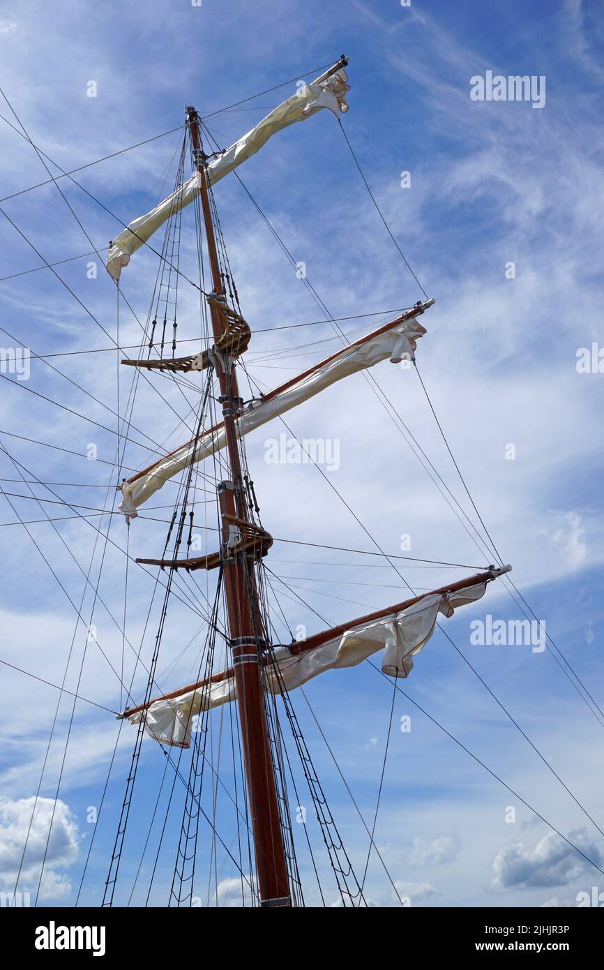 Tall ship mast with rolled sails, sky in background Stock Photo - Alamy