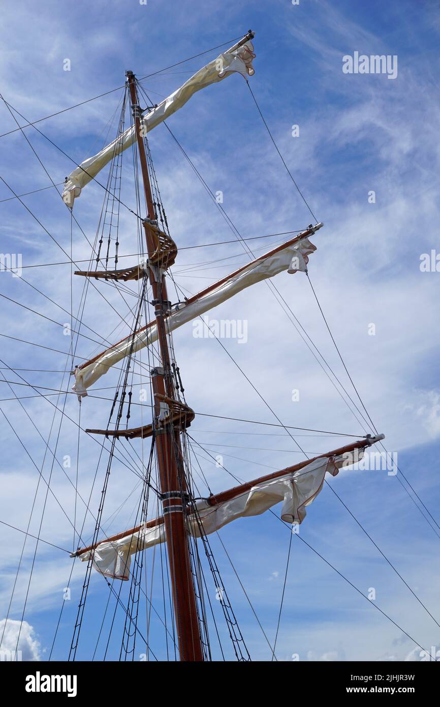 Tall ship mast with rolled sails, sky in background Stock Photo - Alamy