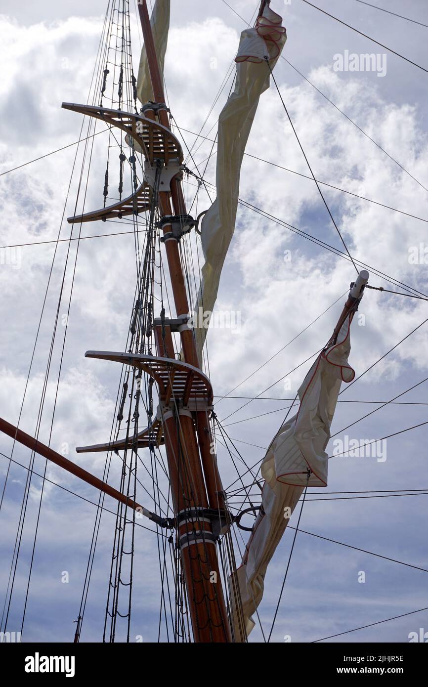 Tall ship mast with rolled sails, sky in background Stock Photo - Alamy