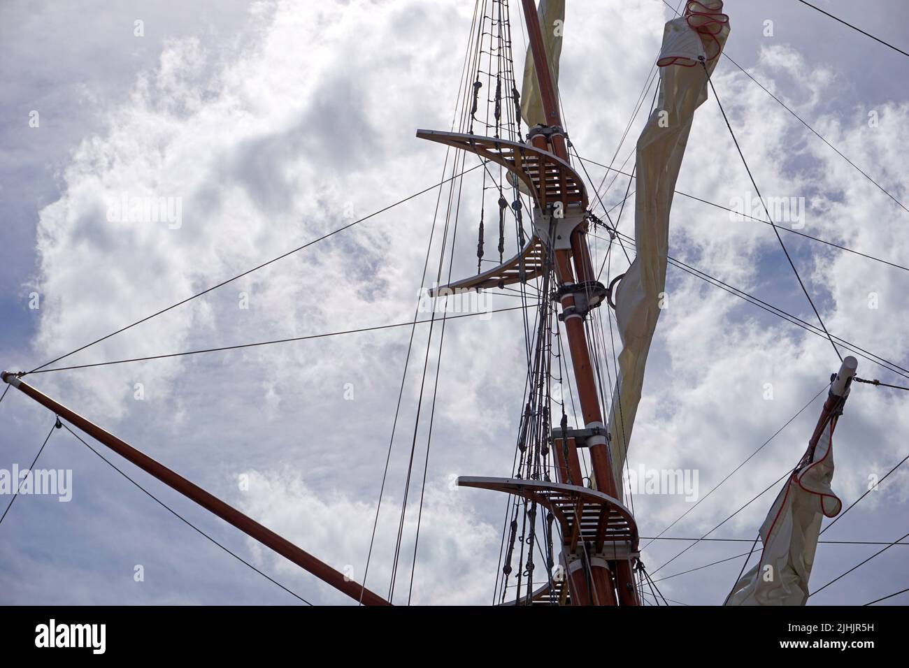 Tall ship mast with rolled sails, sky in background Stock Photo - Alamy