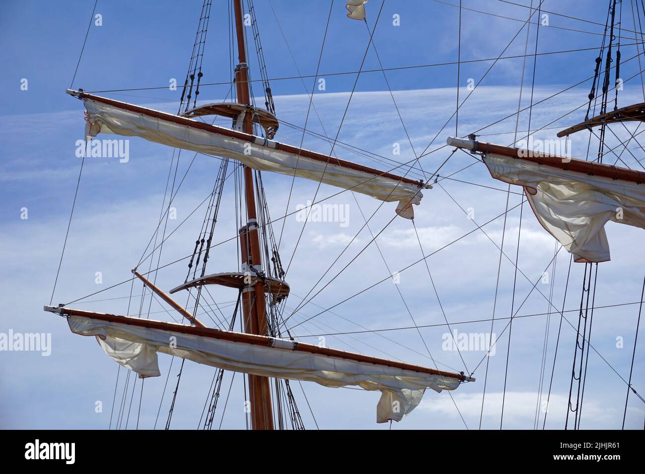 Tall ship mast with rolled sails, sky in background Stock Photo - Alamy