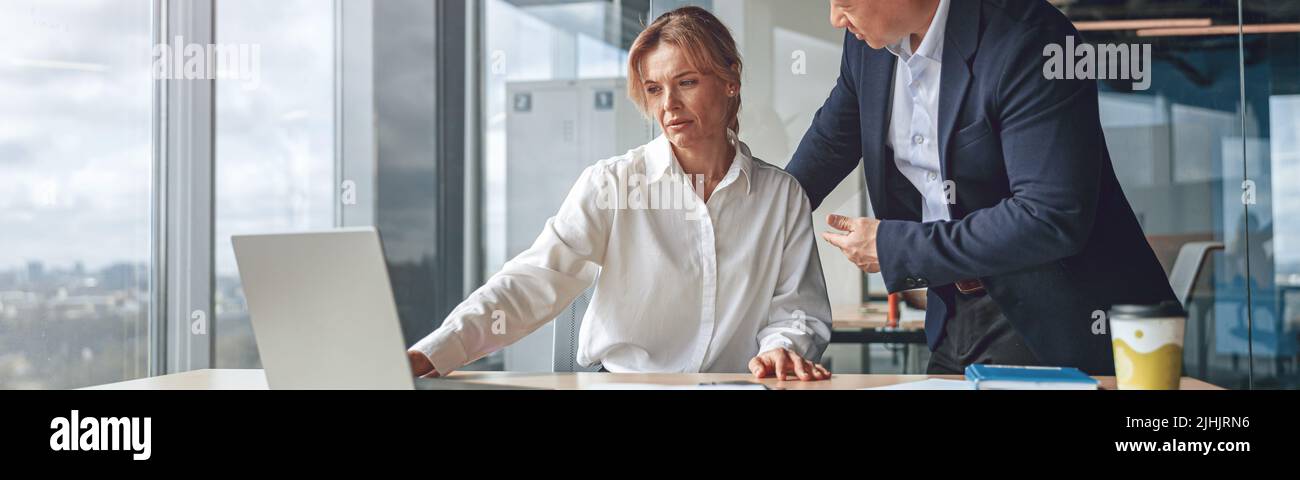 Two confident employees. Working with smile on face together using ...