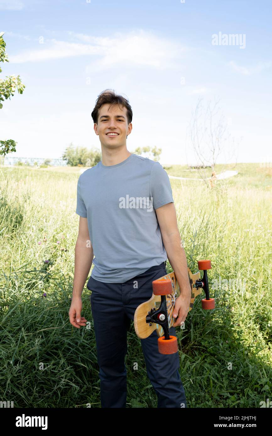 cool young man with grey shirt posing with longboard, skateboard ...