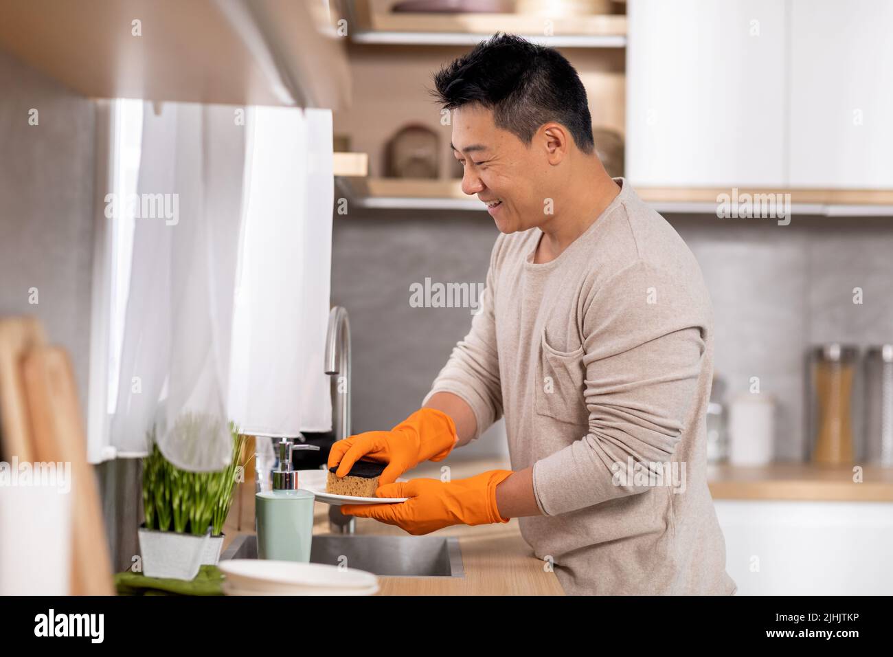 Positive chinese man washing dishes at home Stock Photo - Alamy