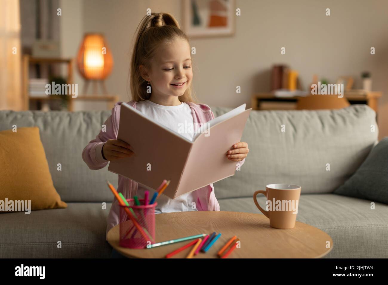 Cheerful Schoolgirl Reading A Book Doing Homework At Home Stock Photo ...