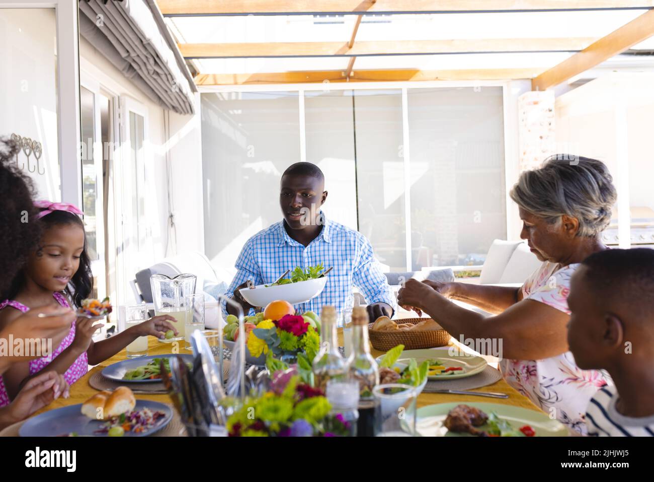 Multiracial multigeneration family eating lunch while sitting at dining ...