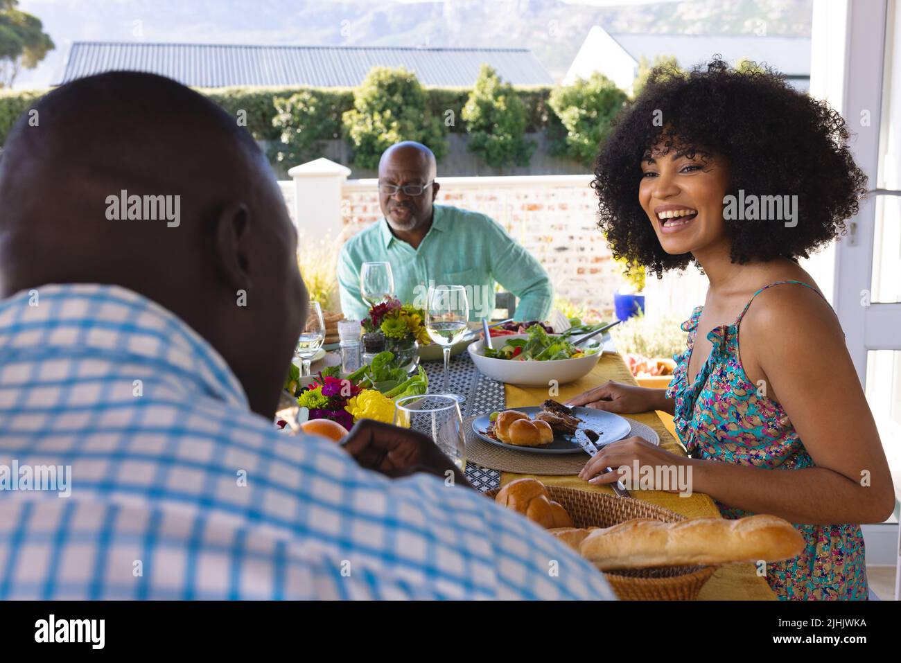 Happy multiracial woman talking with man while having lunch at dining ...