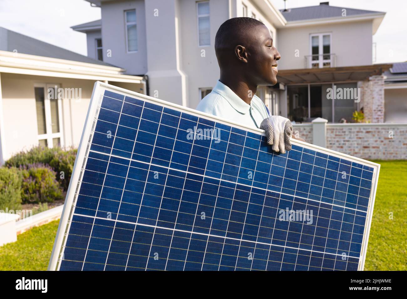 Side view of smiling african american mid adult man carrying solar ...