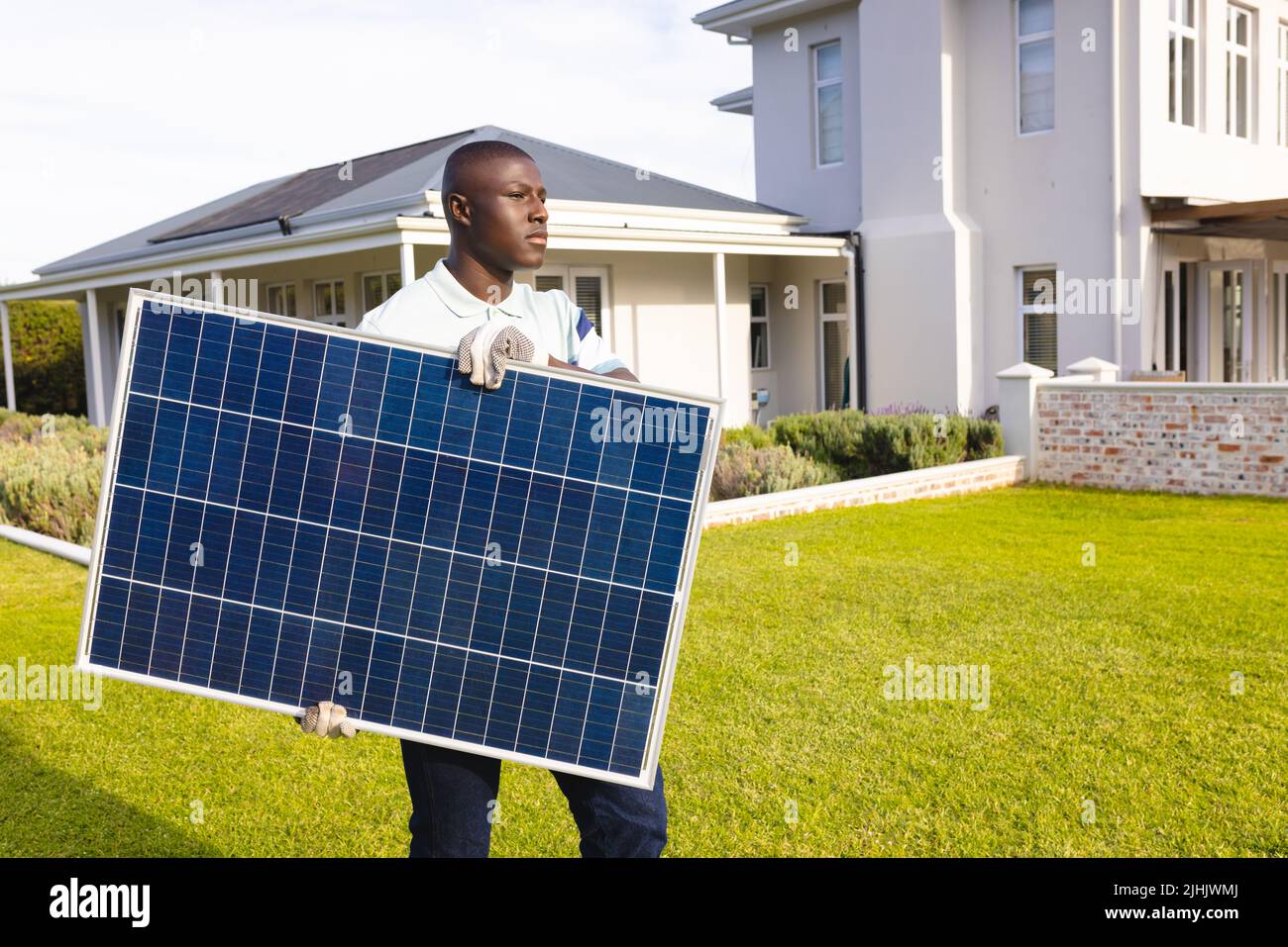 African american mid adult man carrying solar panel while walking in ...