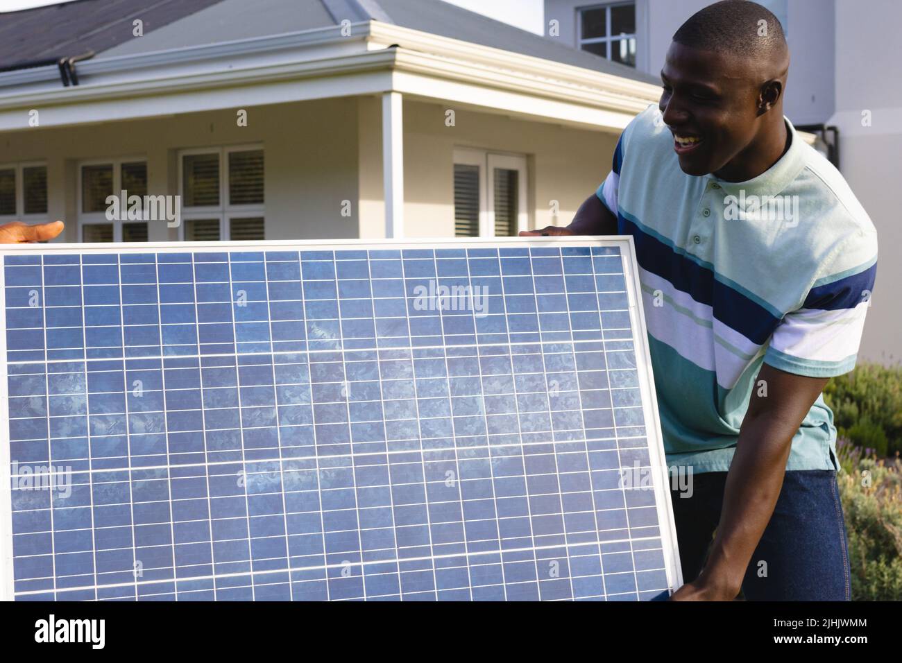 African american mid adult man laughing and carrying solar panel ...
