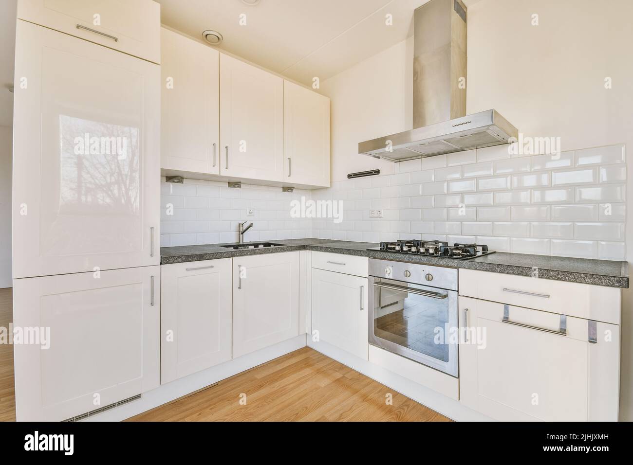 Interior of empty white kitchen with corridor and wooden parquet floor ...