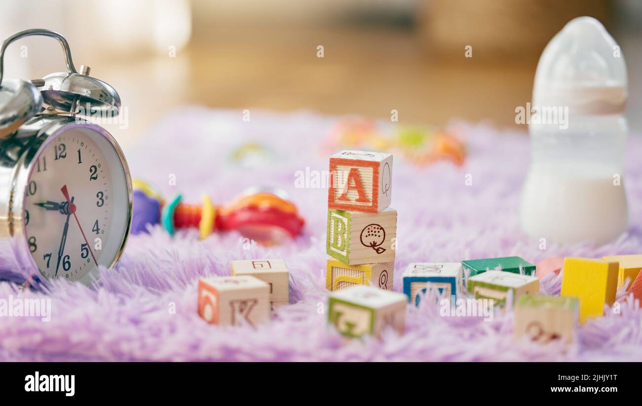 Its baby time. Still life shot of a clock, toys and a baby bottle on a ...