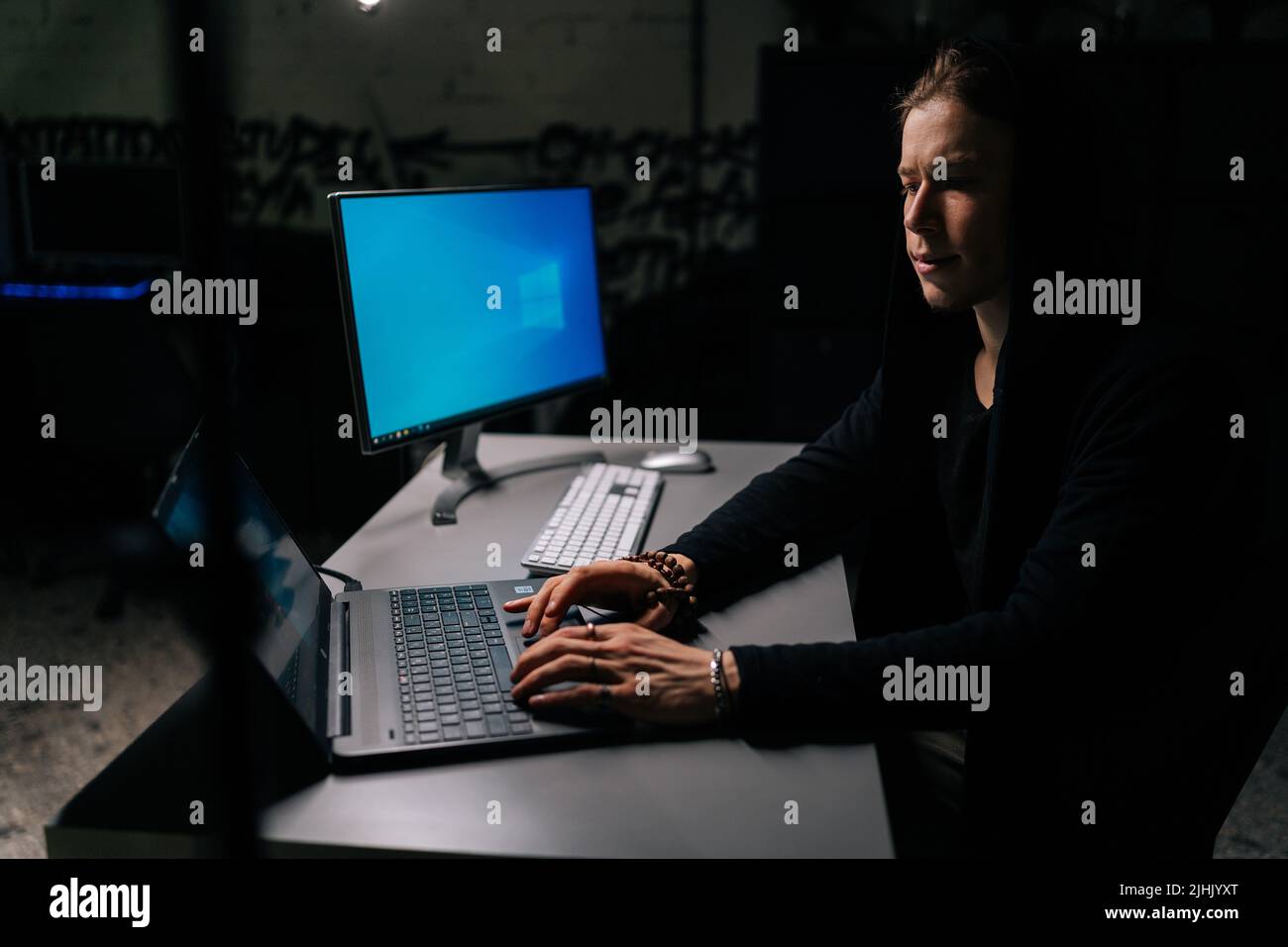 Side view of young hacker man wearing hooded stealing information ...
