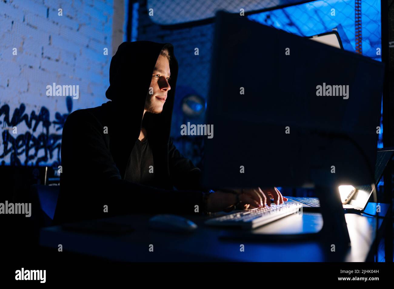 Low-angle view of wanted hacker coding virus ransomware using laptops ...