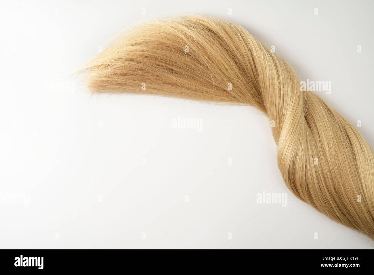 A strand of blonde hair lying on a white background Stock Photo - Alamy