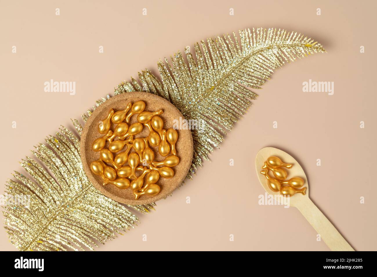 A face serum or oil in golden capsules lying on a beige background ...