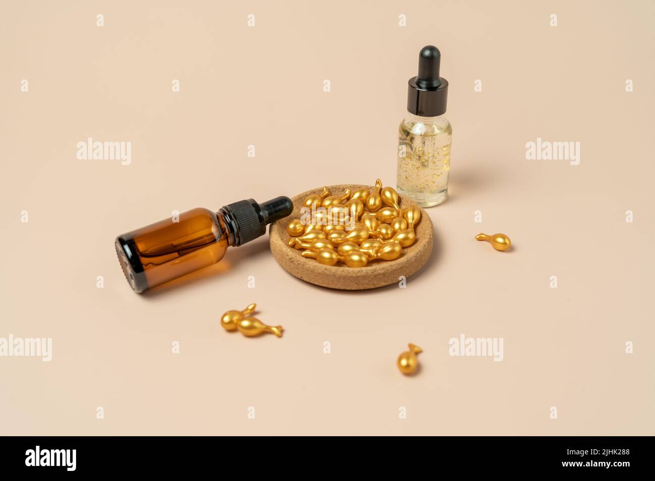 A face serum or oil in golden capsules lying on a beige background ...