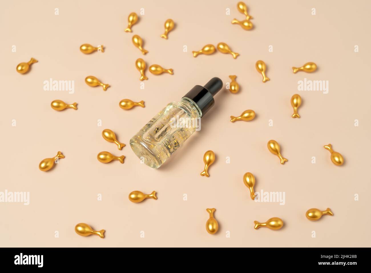 A face serum or oil in golden capsules lying on a beige background ...